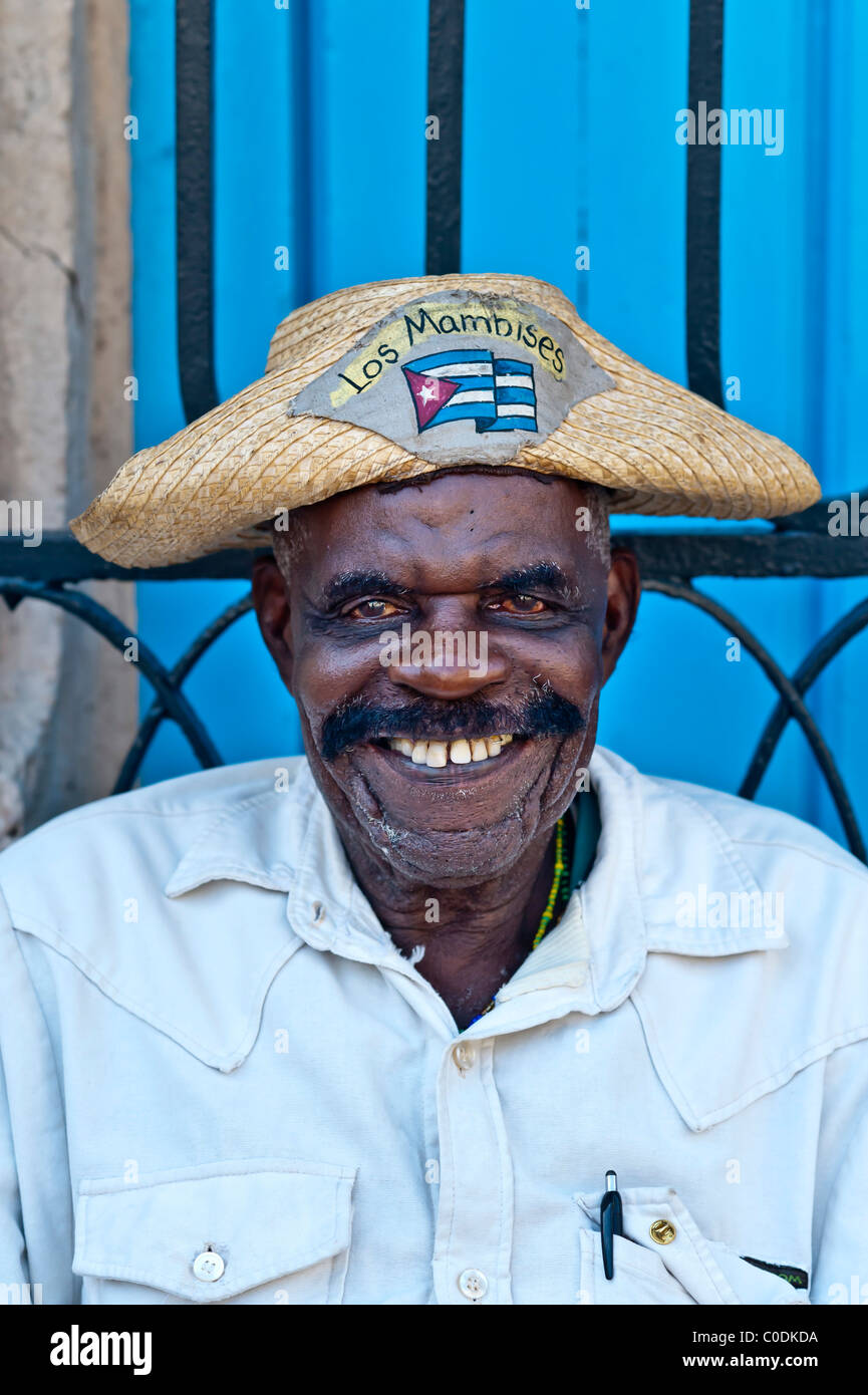 Cuban man sitting in the doorway to his Colonial home with cap. Old ...