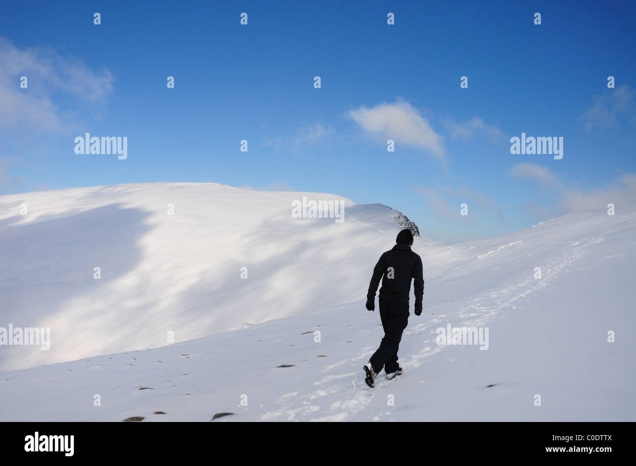 Walker approaching the summit of Helvellyn in winter in the English ...