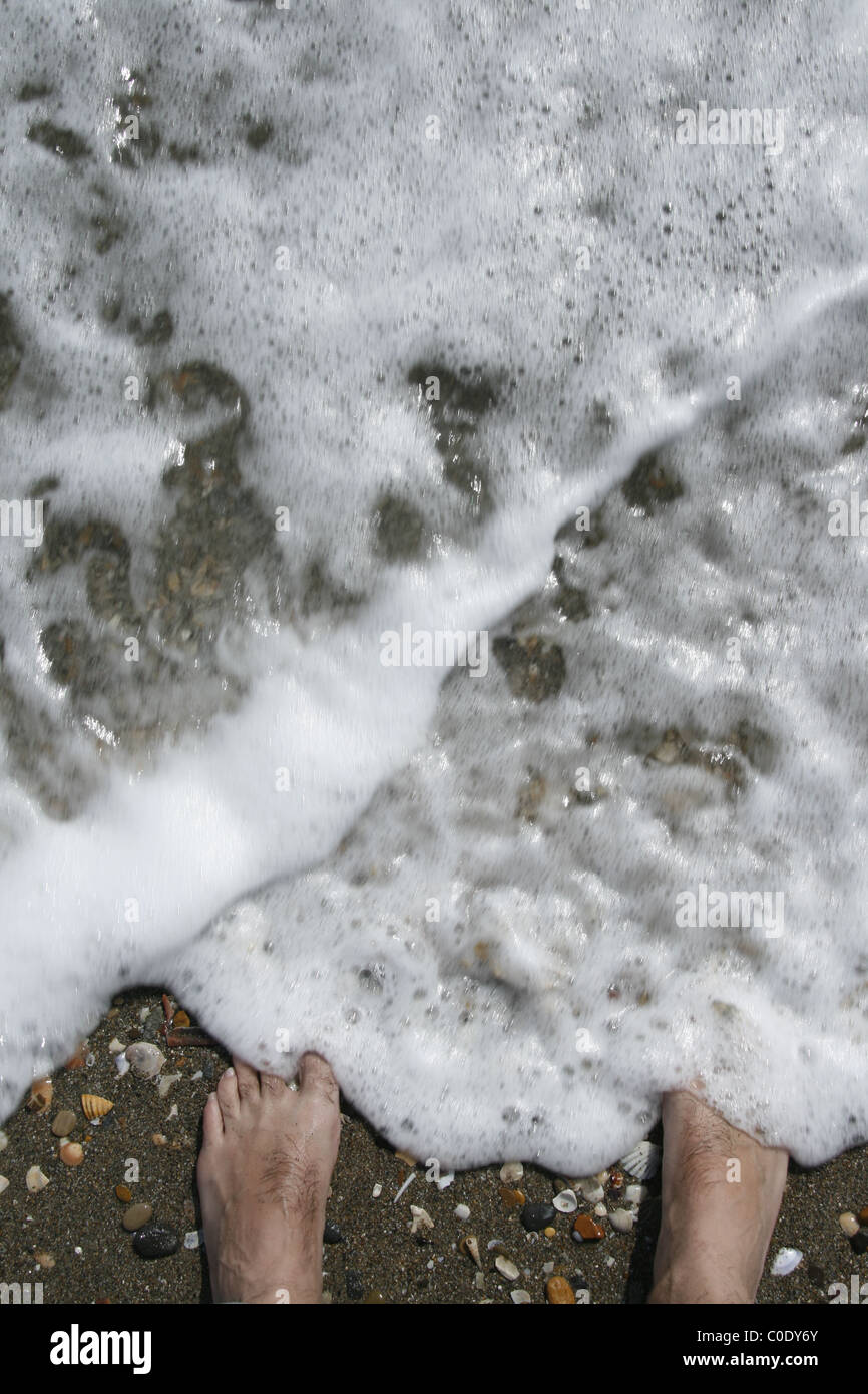 man standing on beach with wave Stock Photo - Alamy