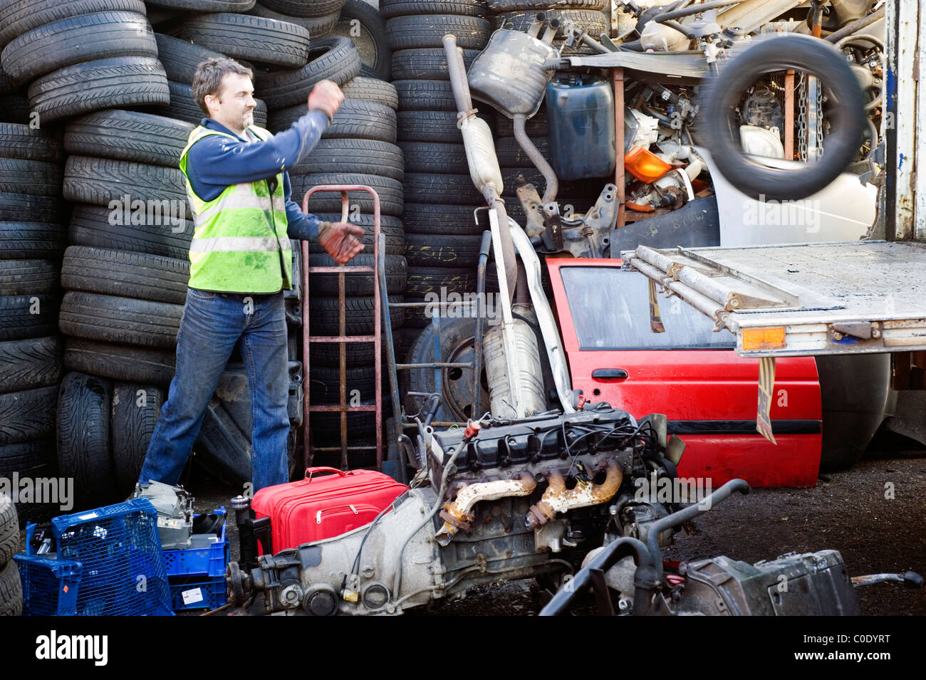 man in scrapyard throwing used tyres into the back of a truck Stock ...