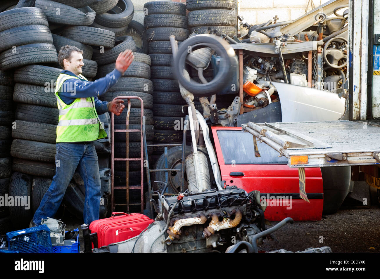 man in scrapyard throwing used tyres into the back of a truck Stock ...