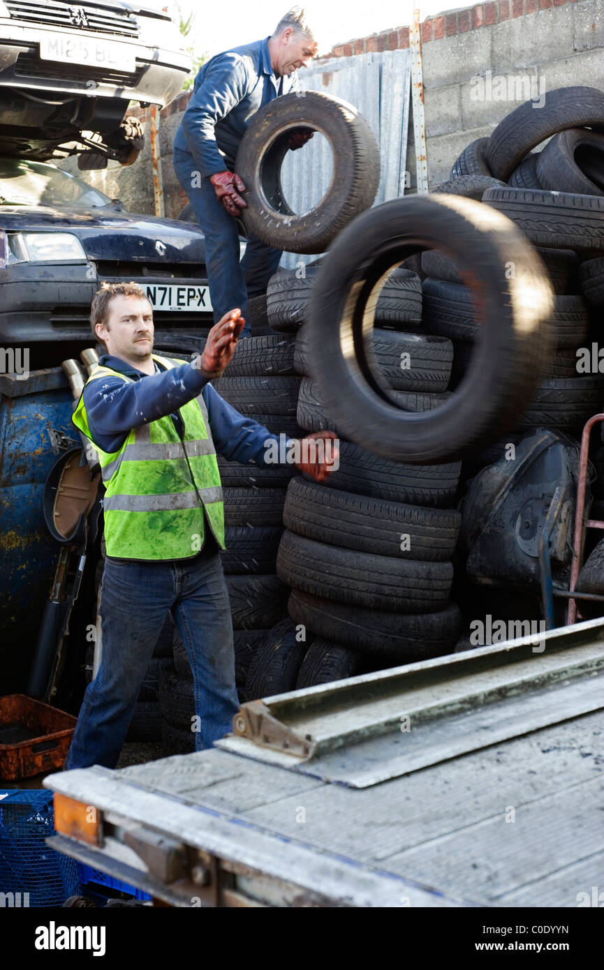 man in scrapyard throwing used tyres into the back of a truck Stock ...