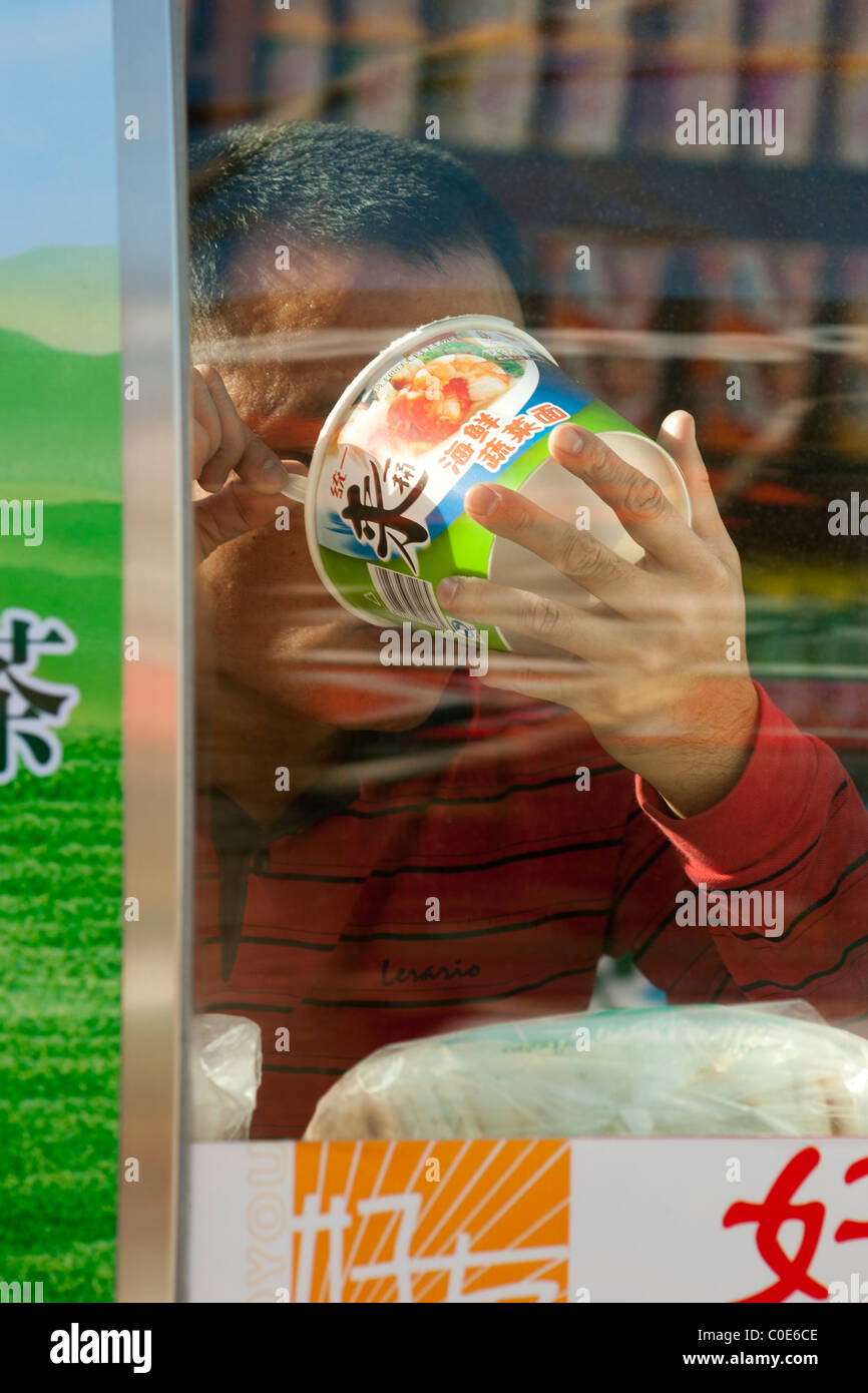 Chinese man eating pot noodles, covering his face with a pot, Beijing ...