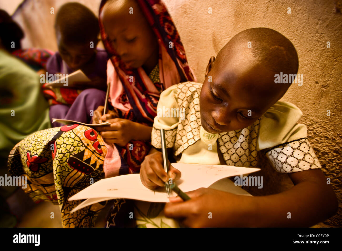 Rwandan girls completing their school work on the school room floor ...
