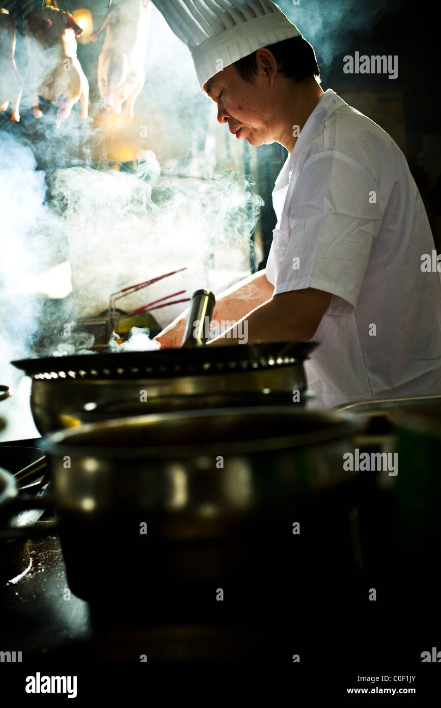 A Chinese chef cooking with smoke in the background Stock Photo - Alamy