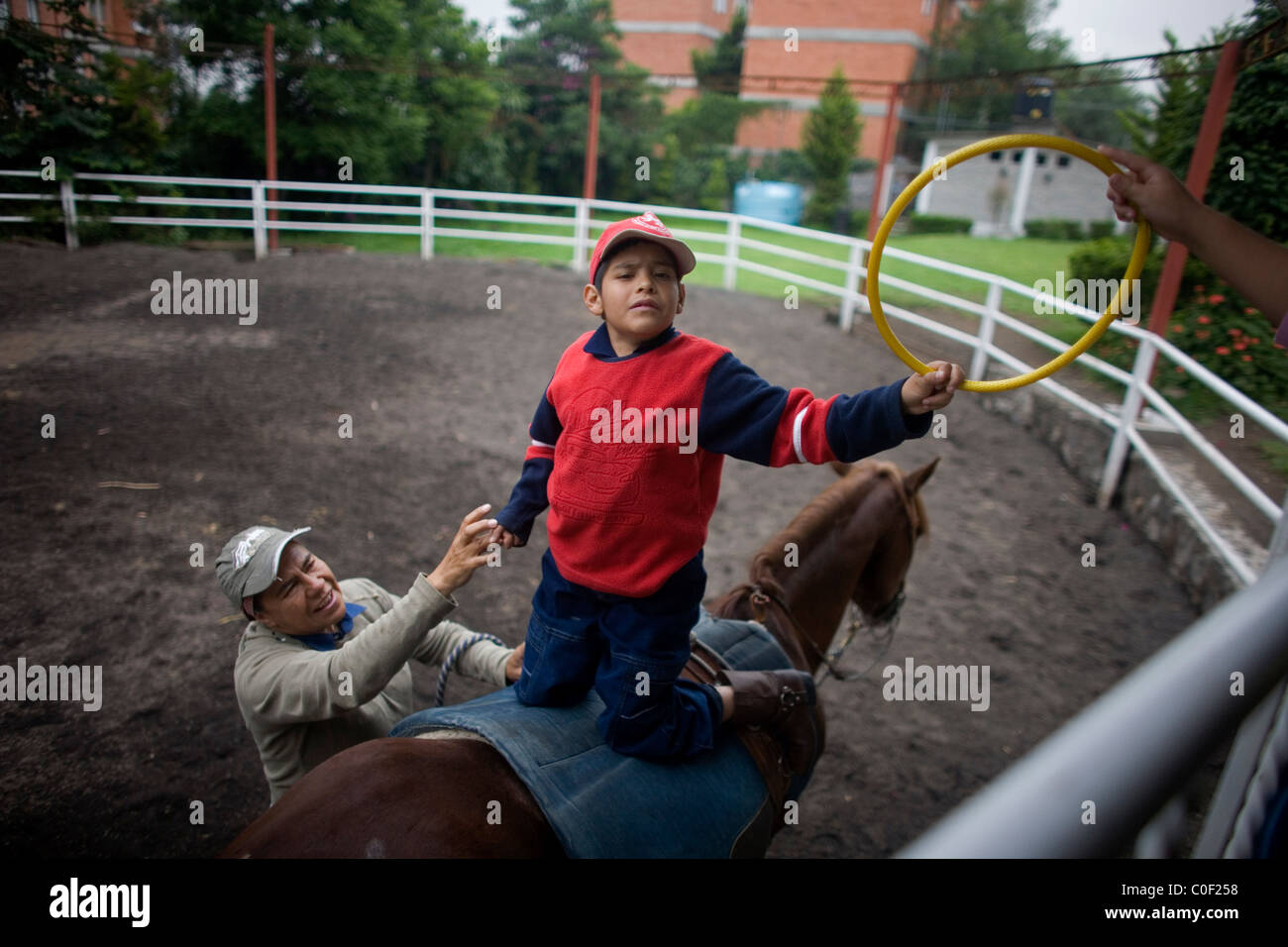 An autistic boy reaches for a hoop as he kneels on a horse during his ...