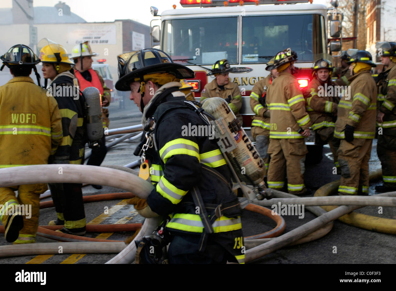 Firefighters drag a hose at scene of a fire in new Jersey Stock Photo ...