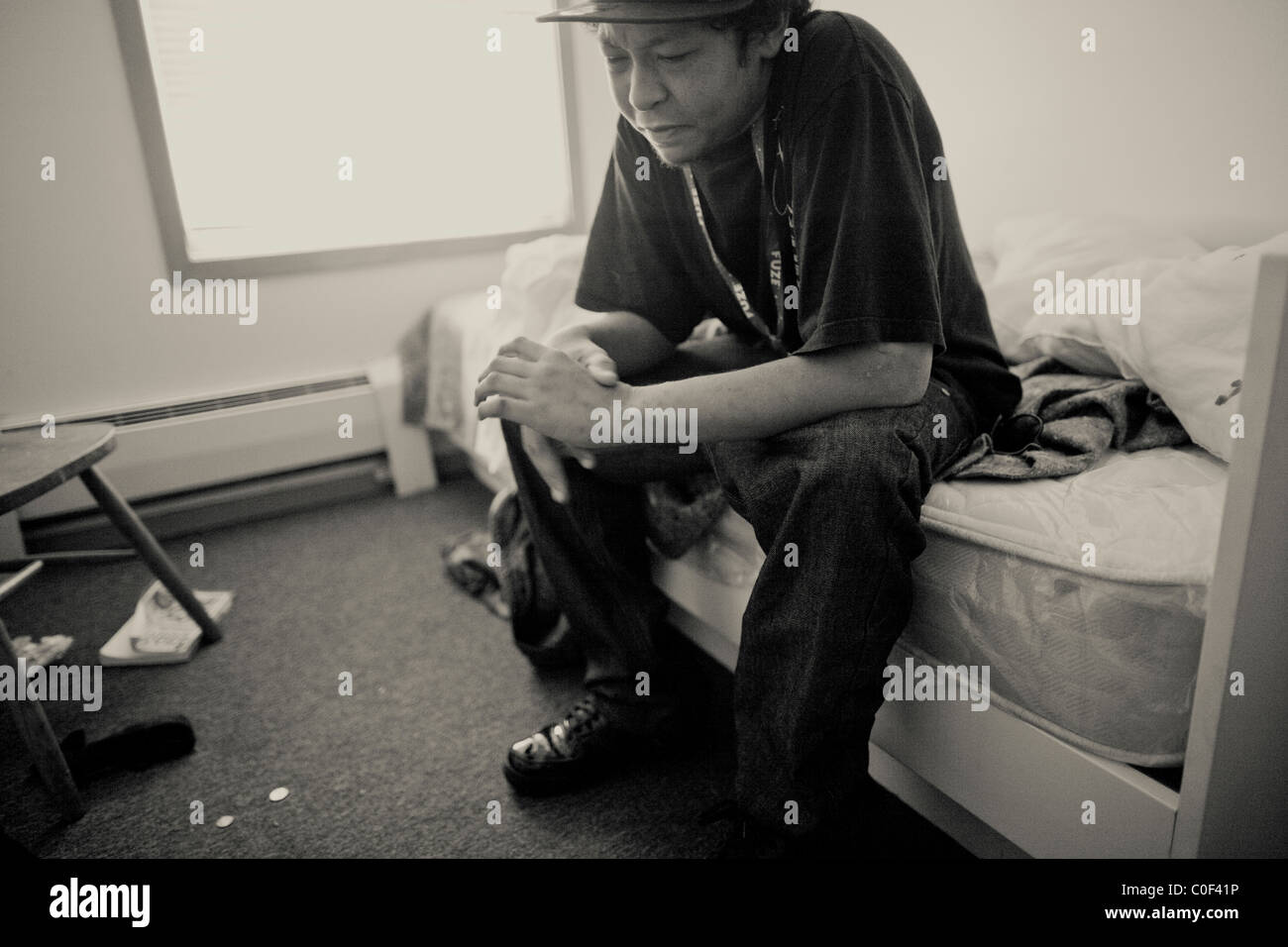 A homeless young adult sits in his room at a temporary housing facility ...