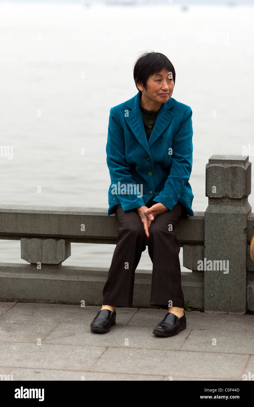 Lonely Chinese lady sitting by the lake Stock Photo - Alamy
