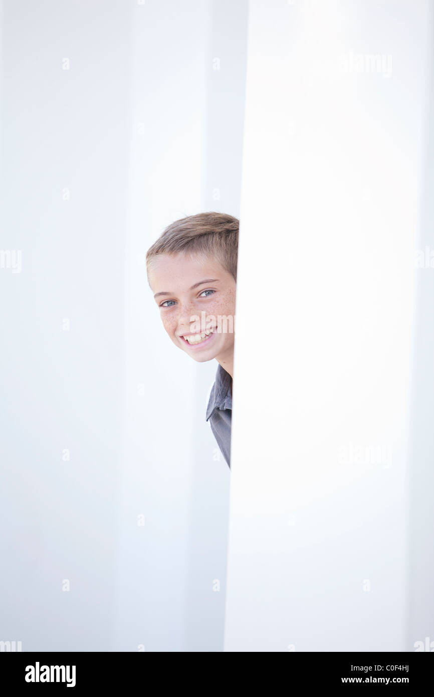 Boy peeking out from behind wall Stock Photo - Alamy