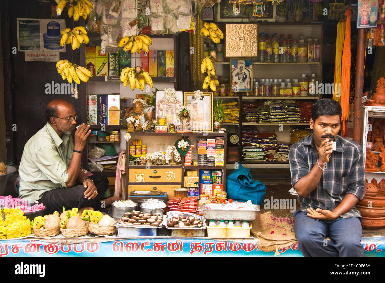 Indian men drinking coffee at his stall with bananas and products ...