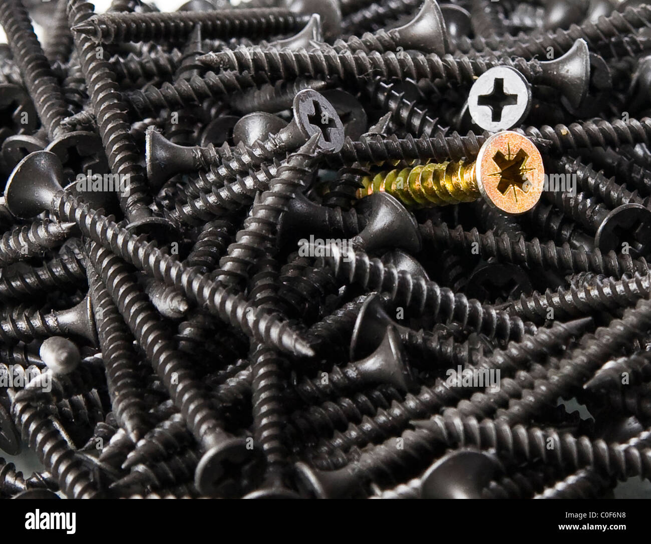 Unique gold screw in to many black Stock Photo - Alamy