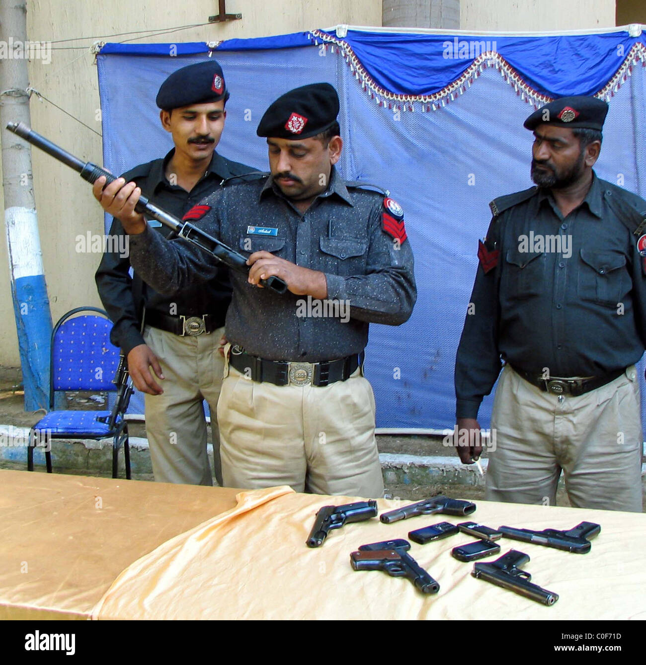 A police official inspects seized weapons which were recovered in raid ...