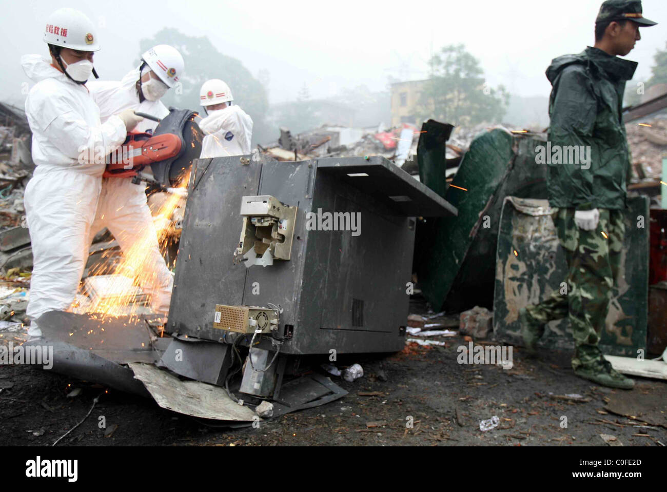 Rescuers dismantle a safe dug out from ruins of a credit cooperative ...