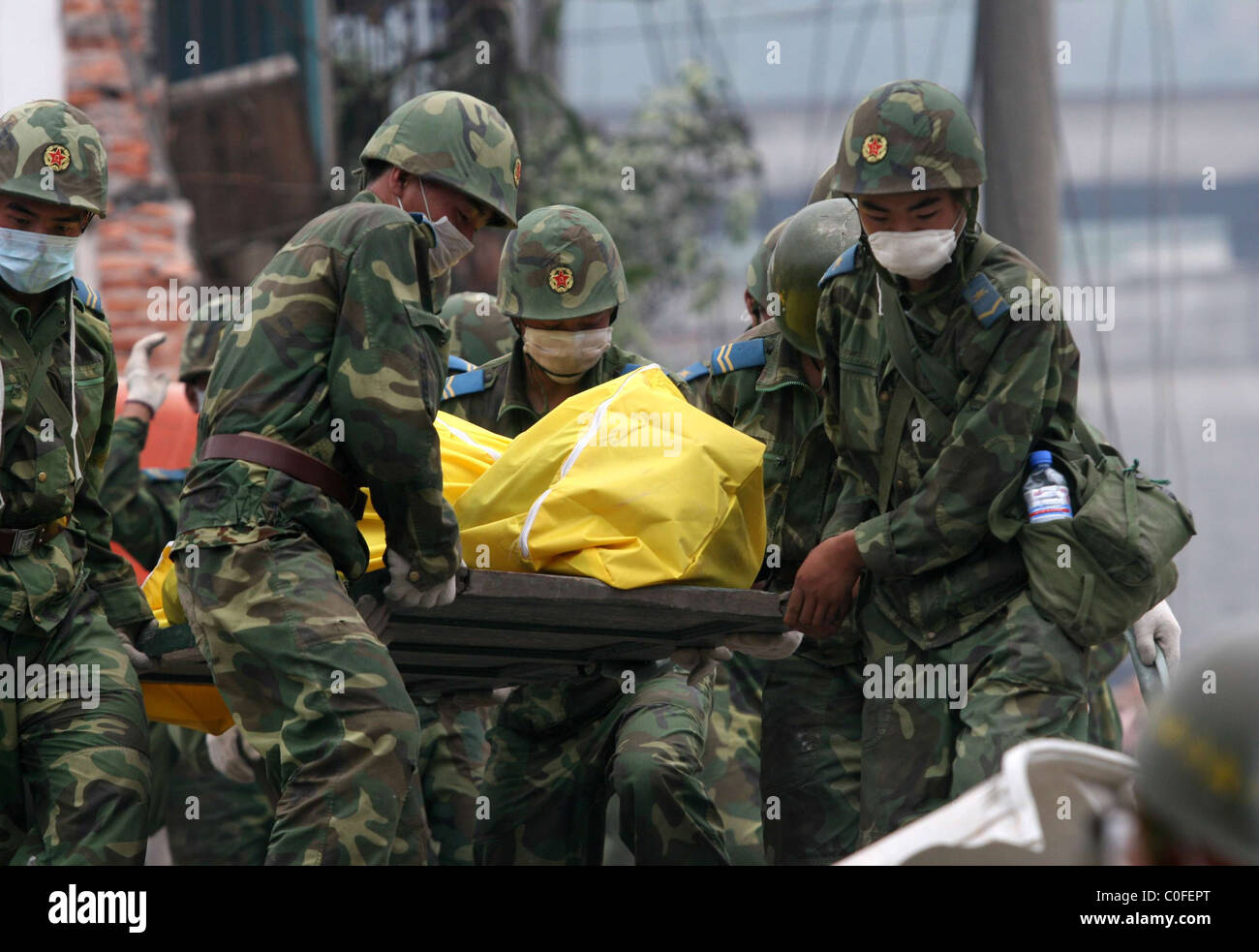 Rescue workers transport a dead body, found in the rubble following the ...
