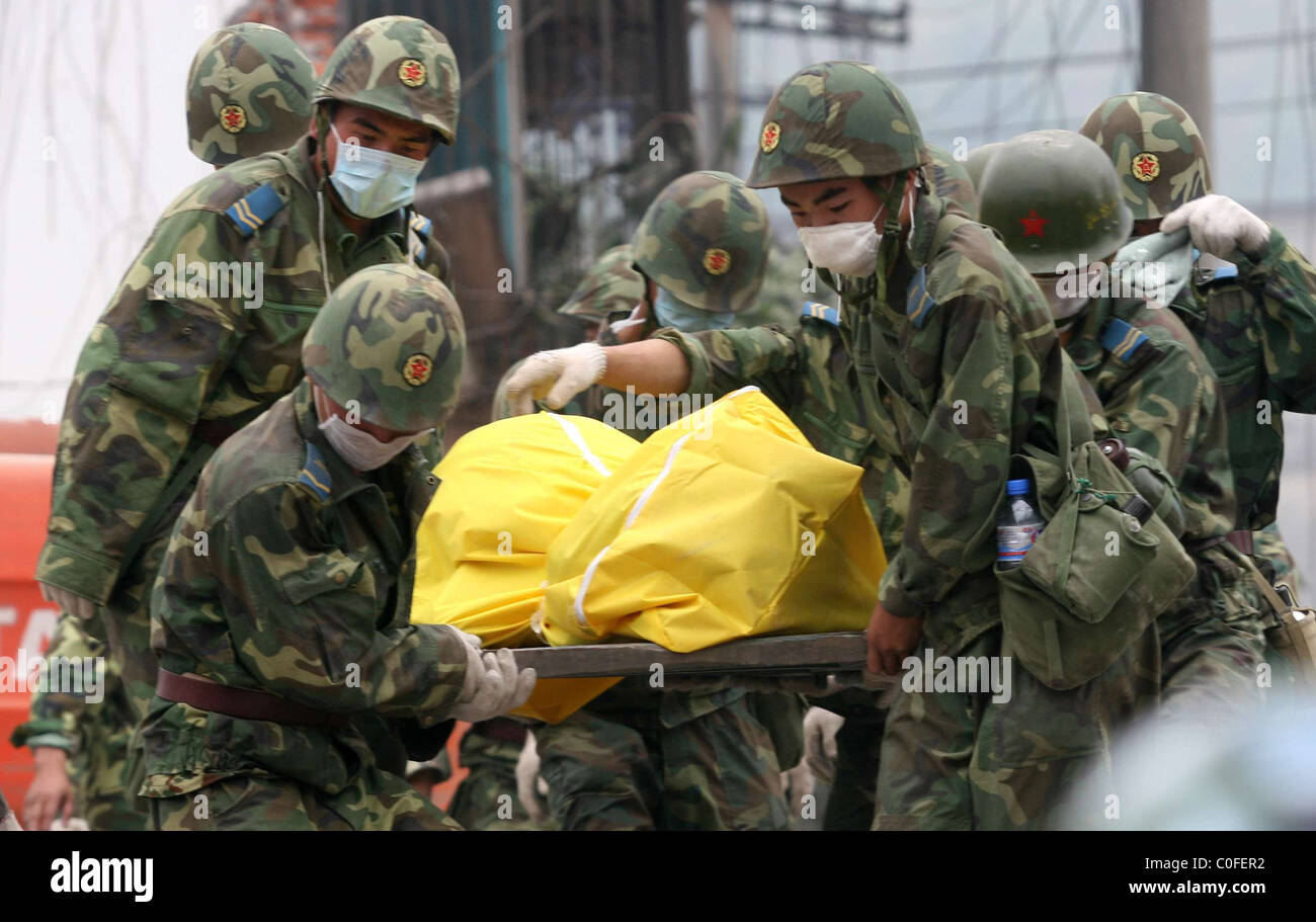 Rescue workers transport a dead body, found in the rubble following the ...