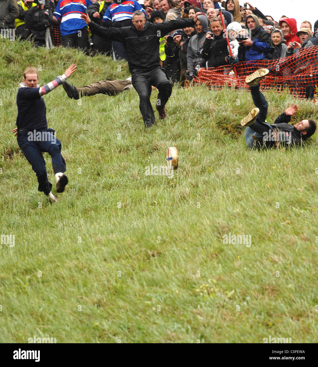 Competitors chase a Double Gloucester Cheese down the steep gradient of ...