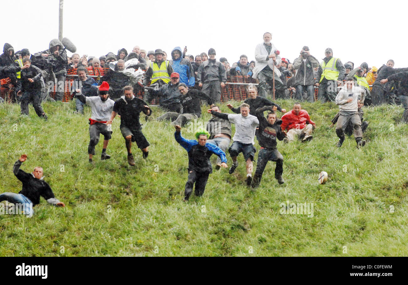 Competitors chase a Double Gloucester Cheese down the steep gradient of ...