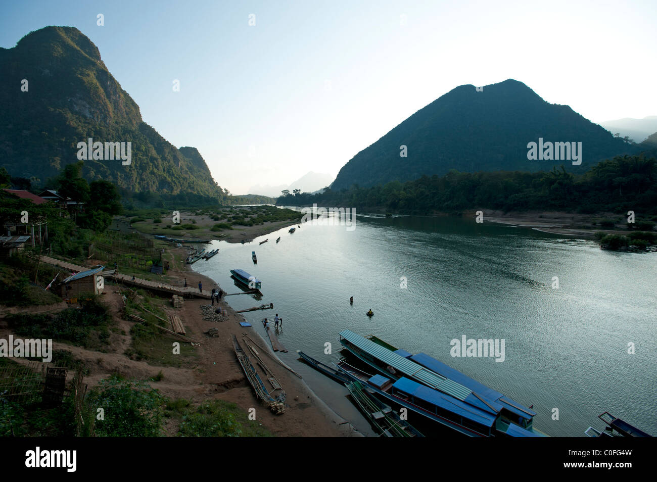 Two people at dusk washing in the river at Muang Ngoi village Northern ...