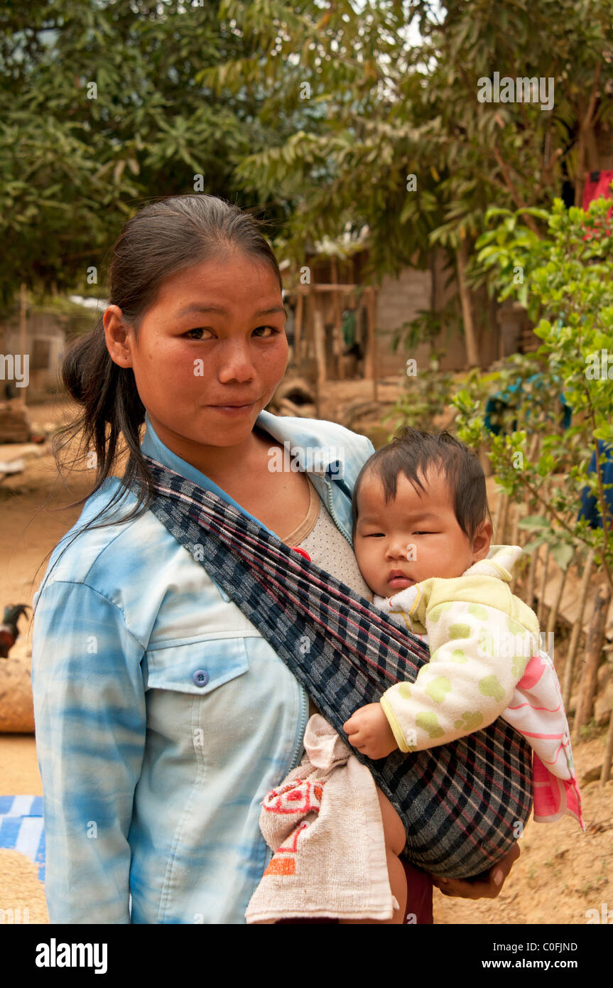 Lao mother carrying her baby in a sling around her shoulders in a ...