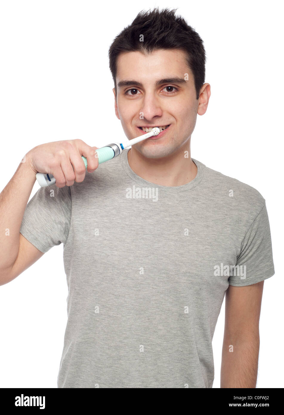 handsome young man brushing his teeth with electric toothbrush ...