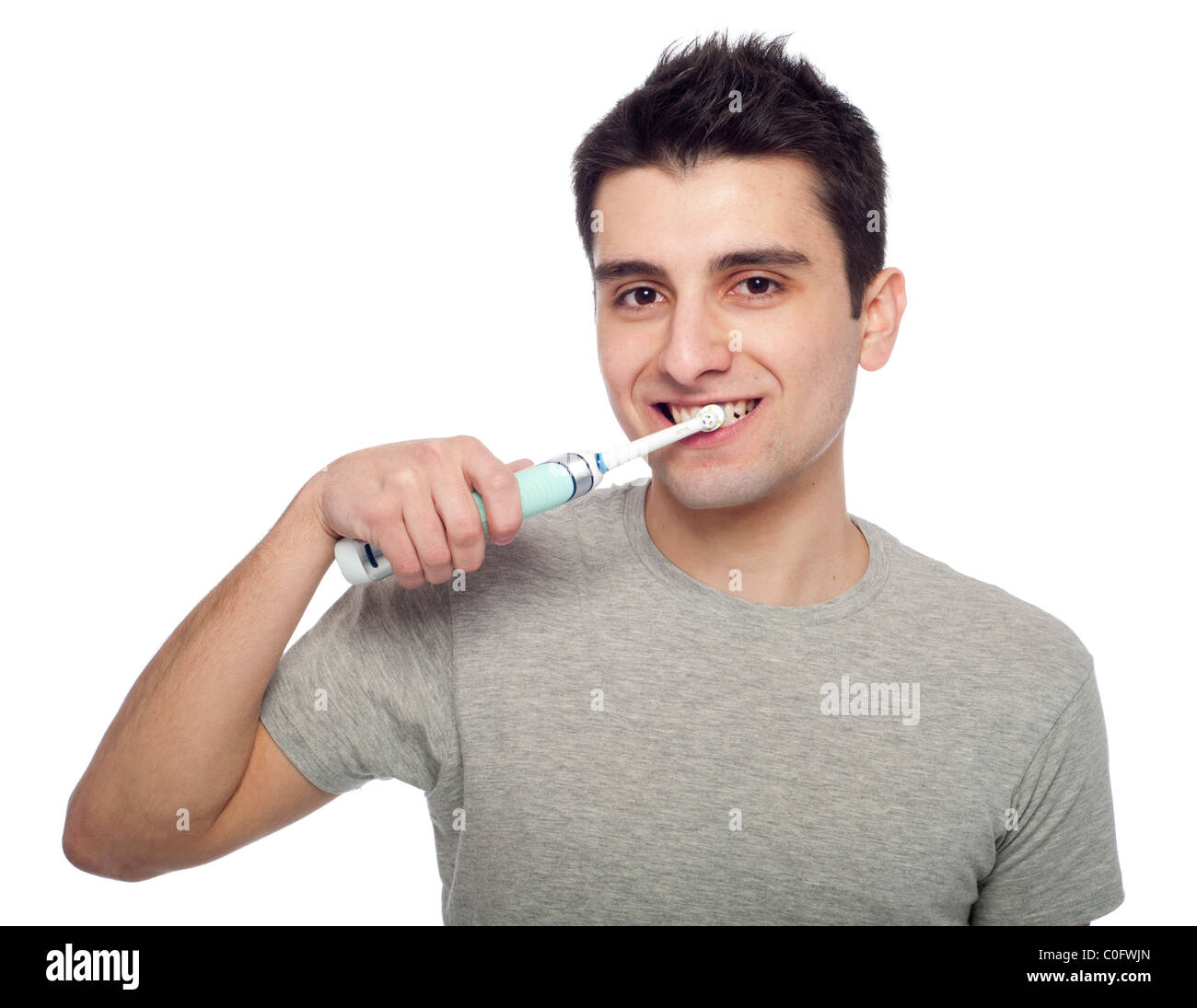 handsome young man brushing his teeth with electric toothbrush ...