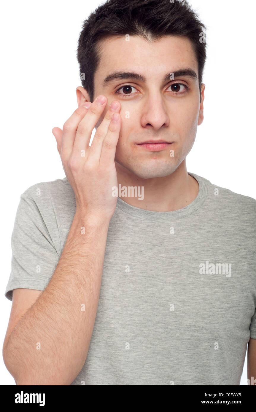 handsome young man applying cream lotion on face (isolated on white ...