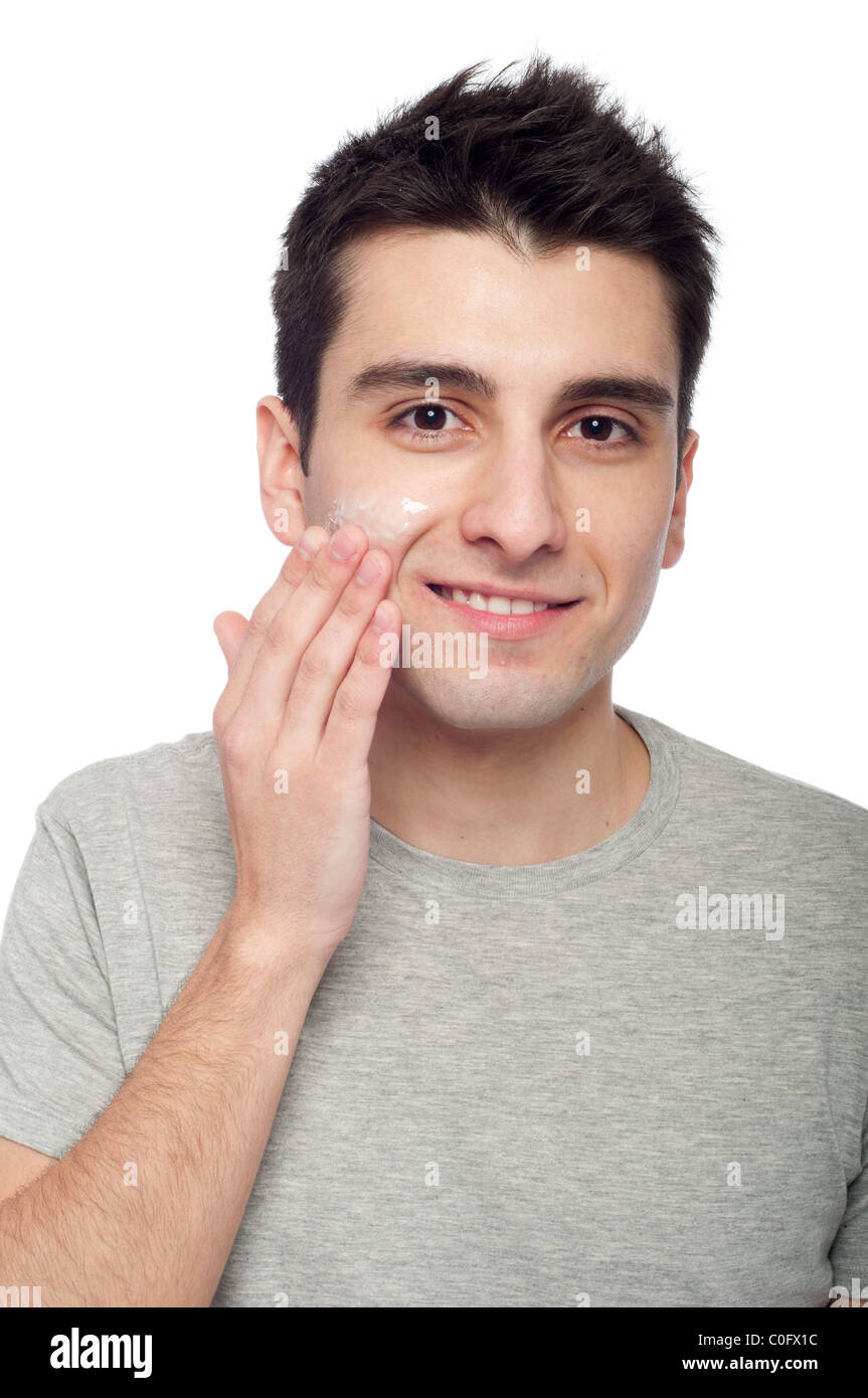 handsome young man applying cream lotion on face (isolated on white ...
