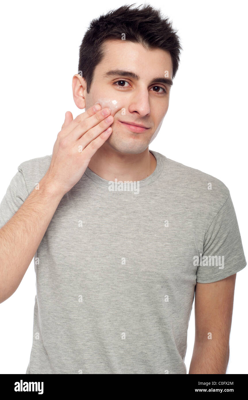 handsome young man applying cream lotion on face (isolated on white ...