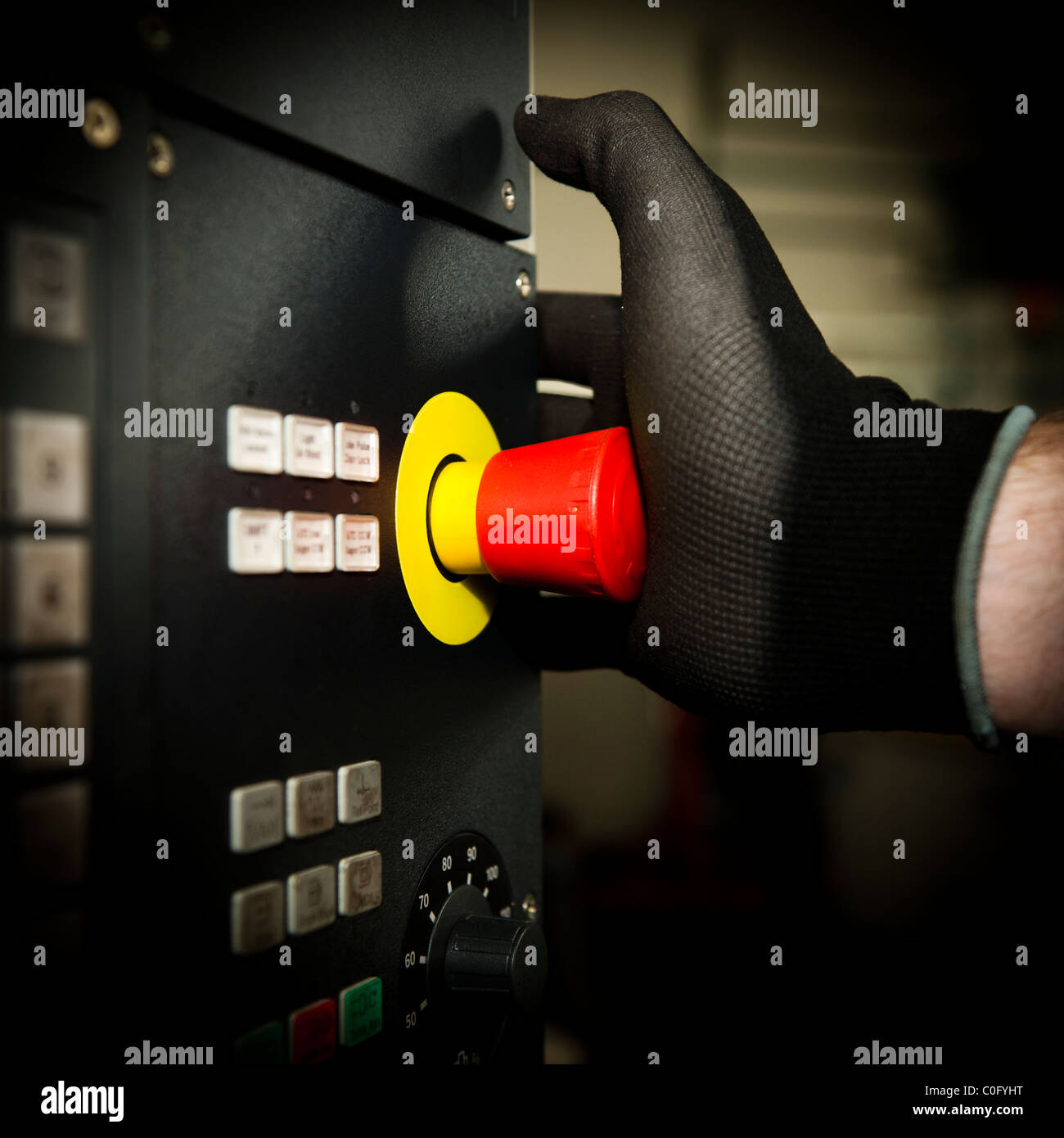 a man pressing the emergency stop button on a machine in a factory or ... a man pressing the emergency stop button on a machine in a factory or ...