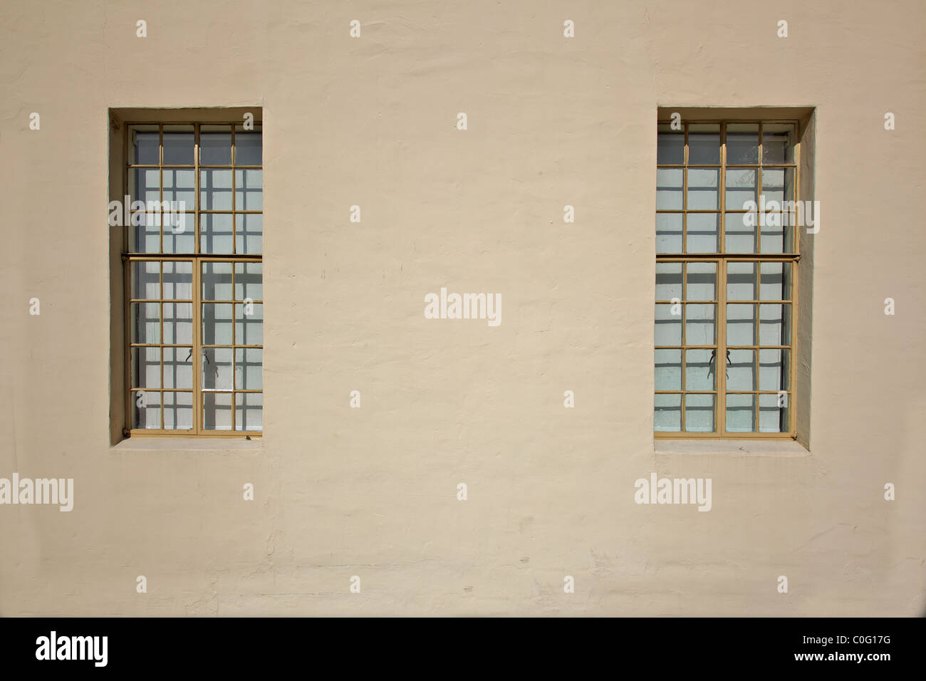 Two multi-paned windows on a beige stucco wall Stock Photo - Alamy