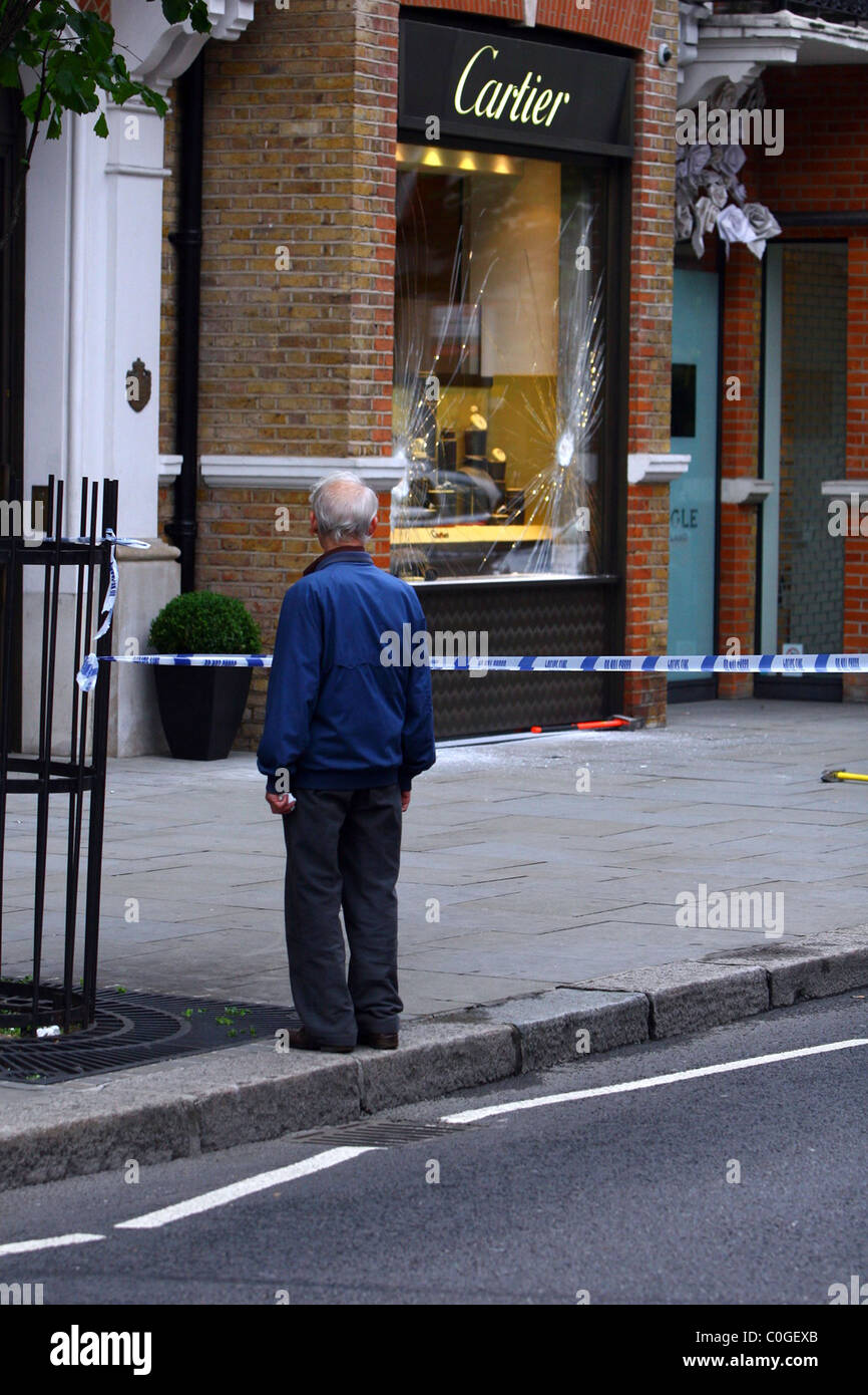 A man looks on at the smashed shop exterior from behind a Police cordon ...