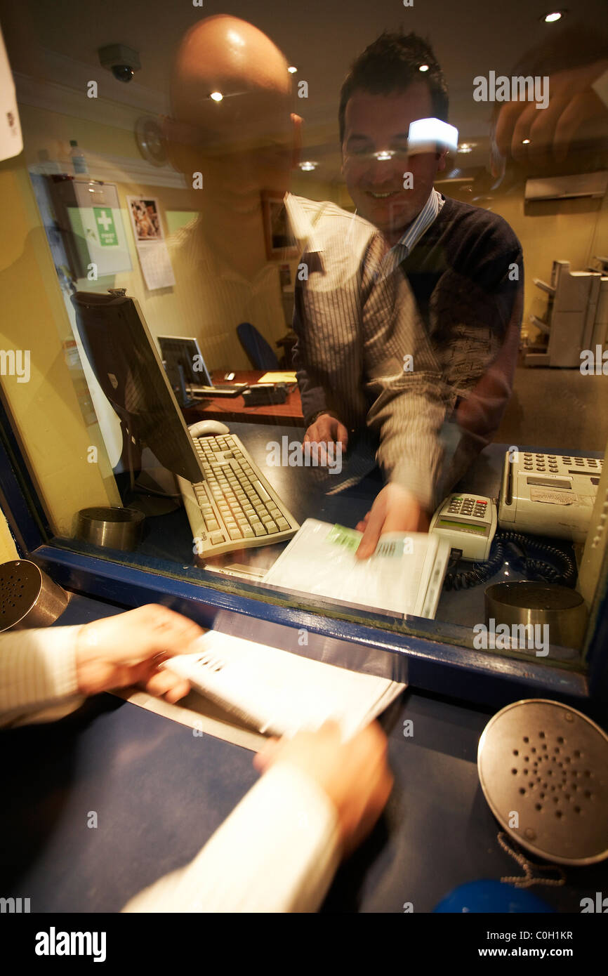 Man passing documents through counter window Stock Photo - Alamy