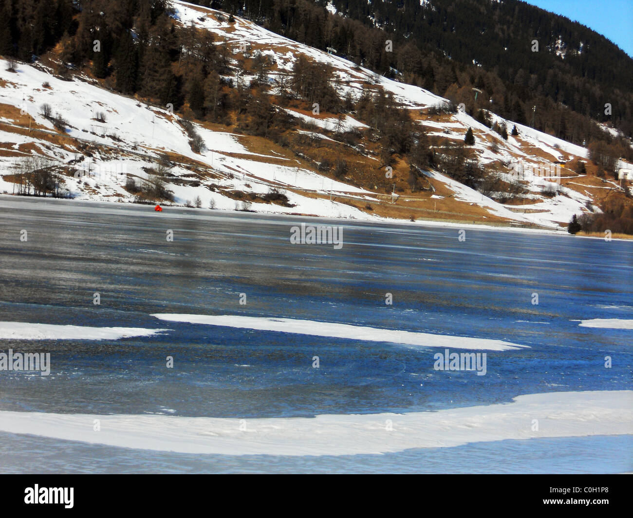 frozen lake in winter with blue sky and snow-capped mountains ...