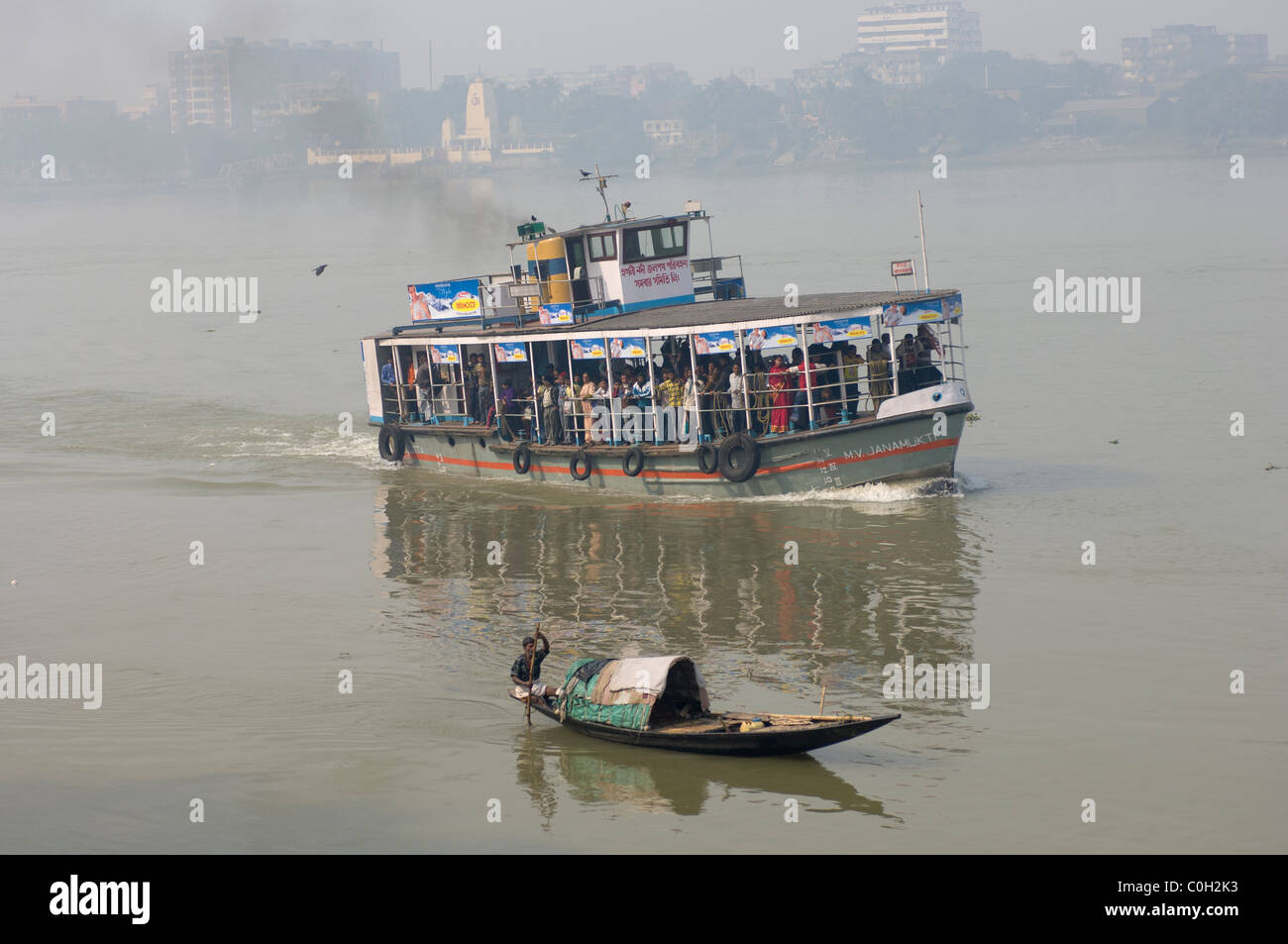 Crowded ferry passing a small boat on the Hooghly River, Kolkata ...