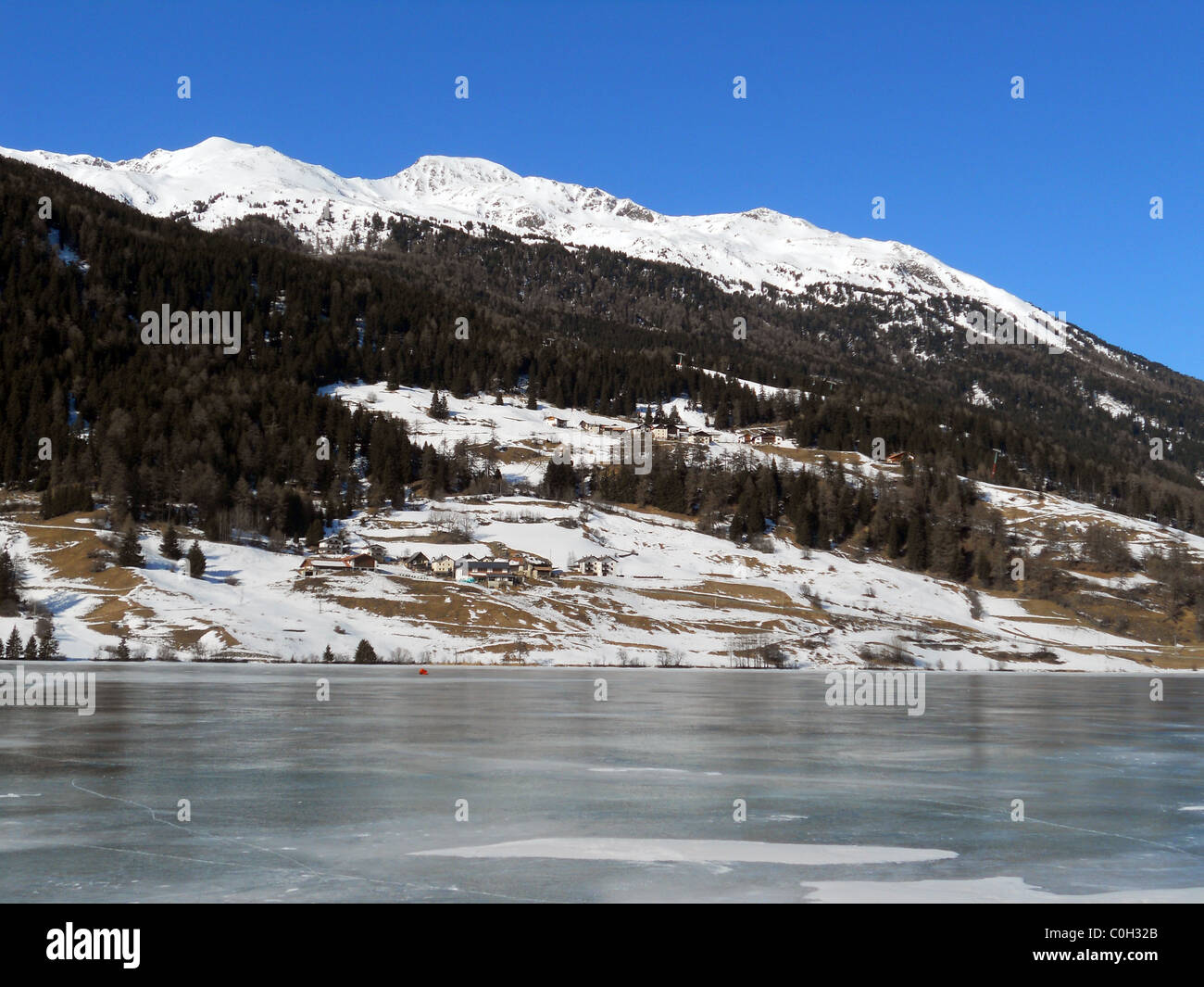 frozen lake in winter with blue sky and snow-capped mountains ...