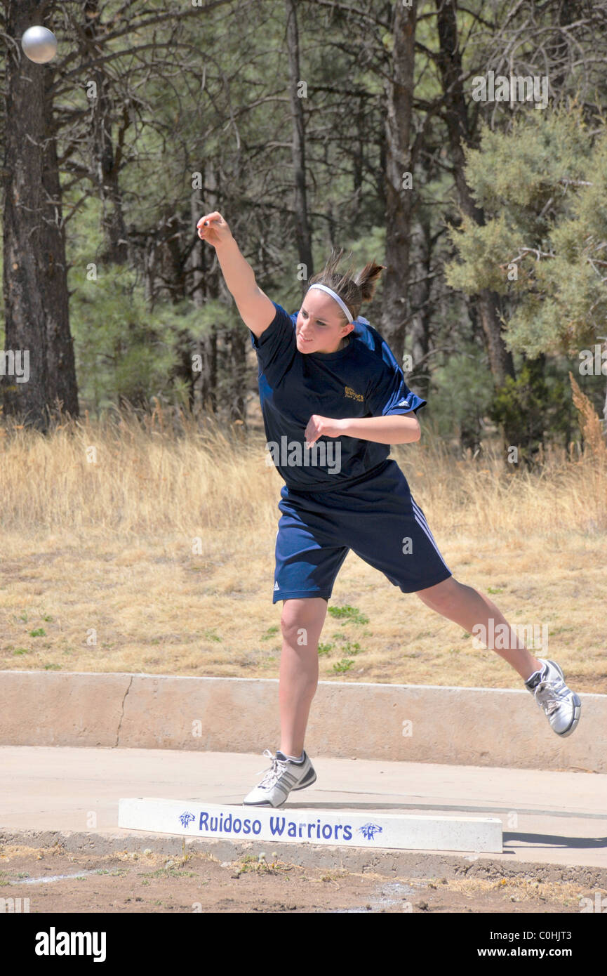 Teenage high school girl athlete hurling a shot put at a track and ...