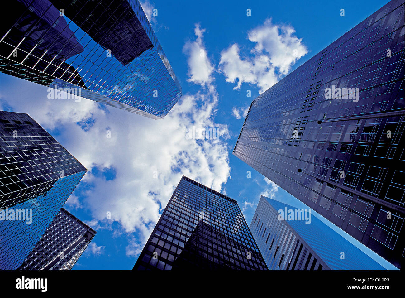 Looking up between modern skyscrapers in lower Manhattan with blue sky ...