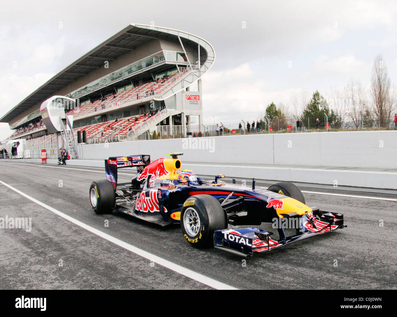 Mark Webber (AUS) in the Red Bull RB7 Formula One racecar in front of ...