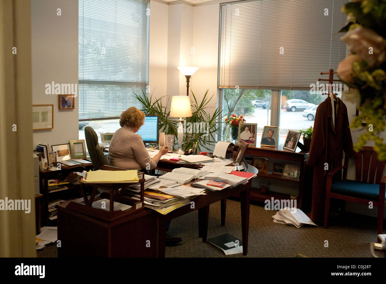 Busy female attorney works in her office surrounded by piles of ...