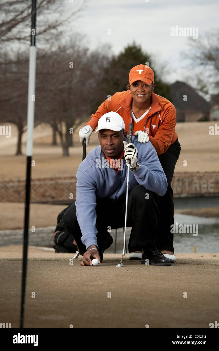 African-American married couple play golf together on a course near ...