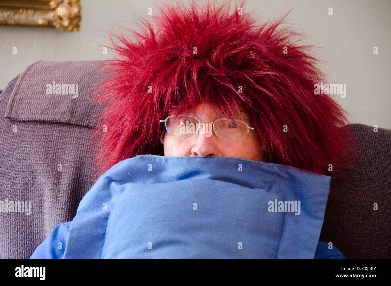 An elderly man acts silly by putting on a red fuzzy wig. USA Stock ...