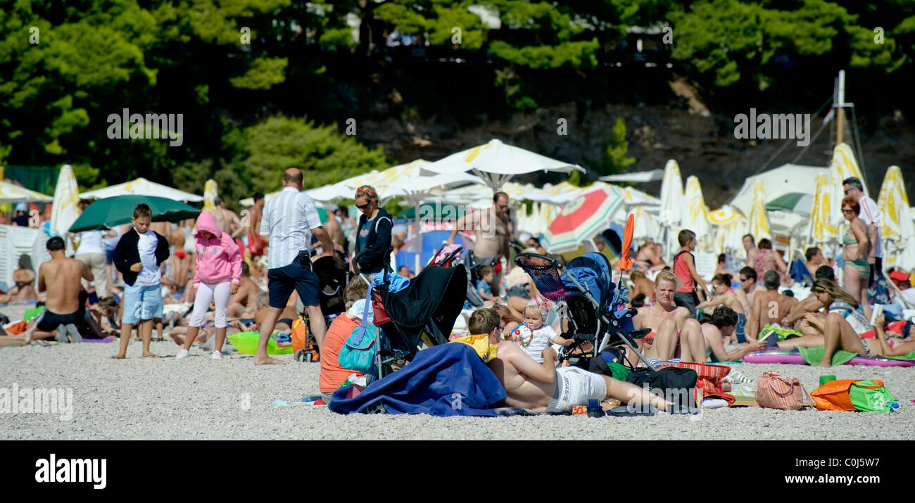 crowds sunbathe on the shingle sand peninsula of Zlatni Rat, near Bol ...