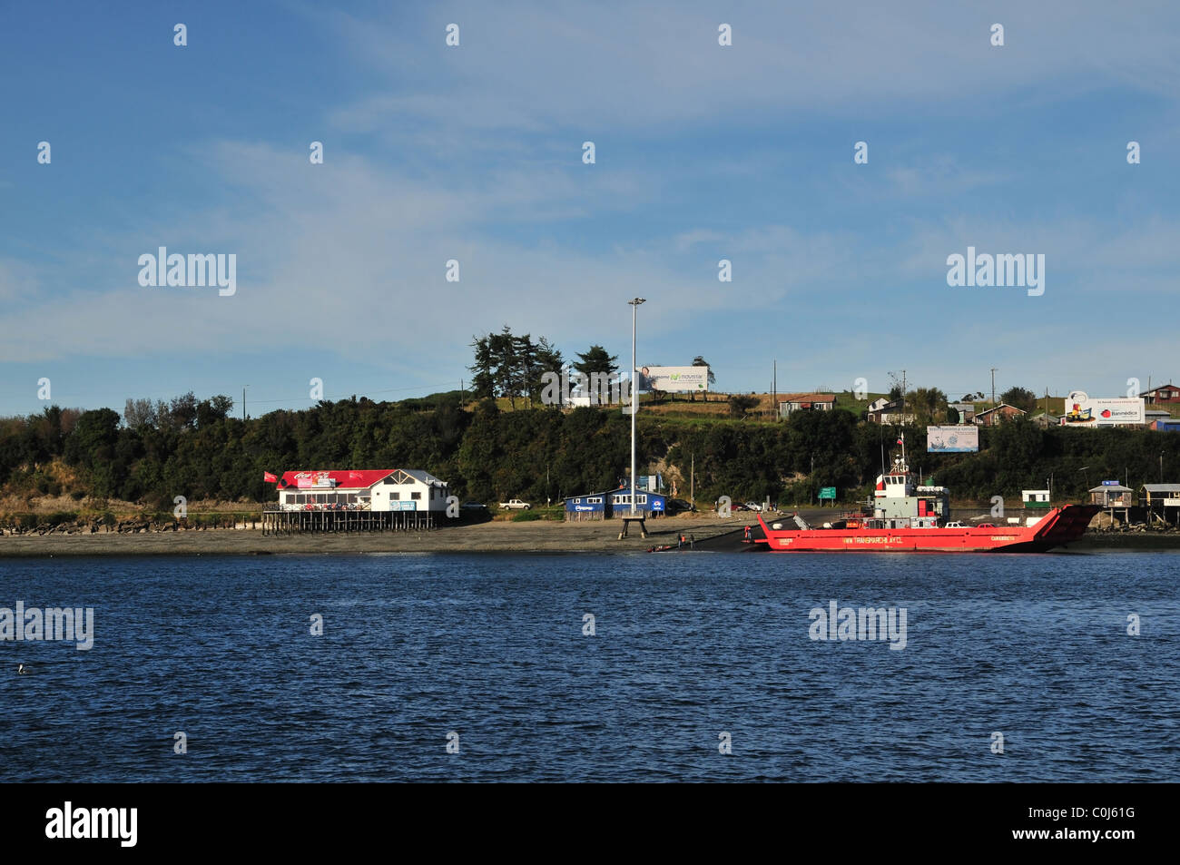 Chacao Channel view of green cliffs, cafe palafitos and red vehicle ...