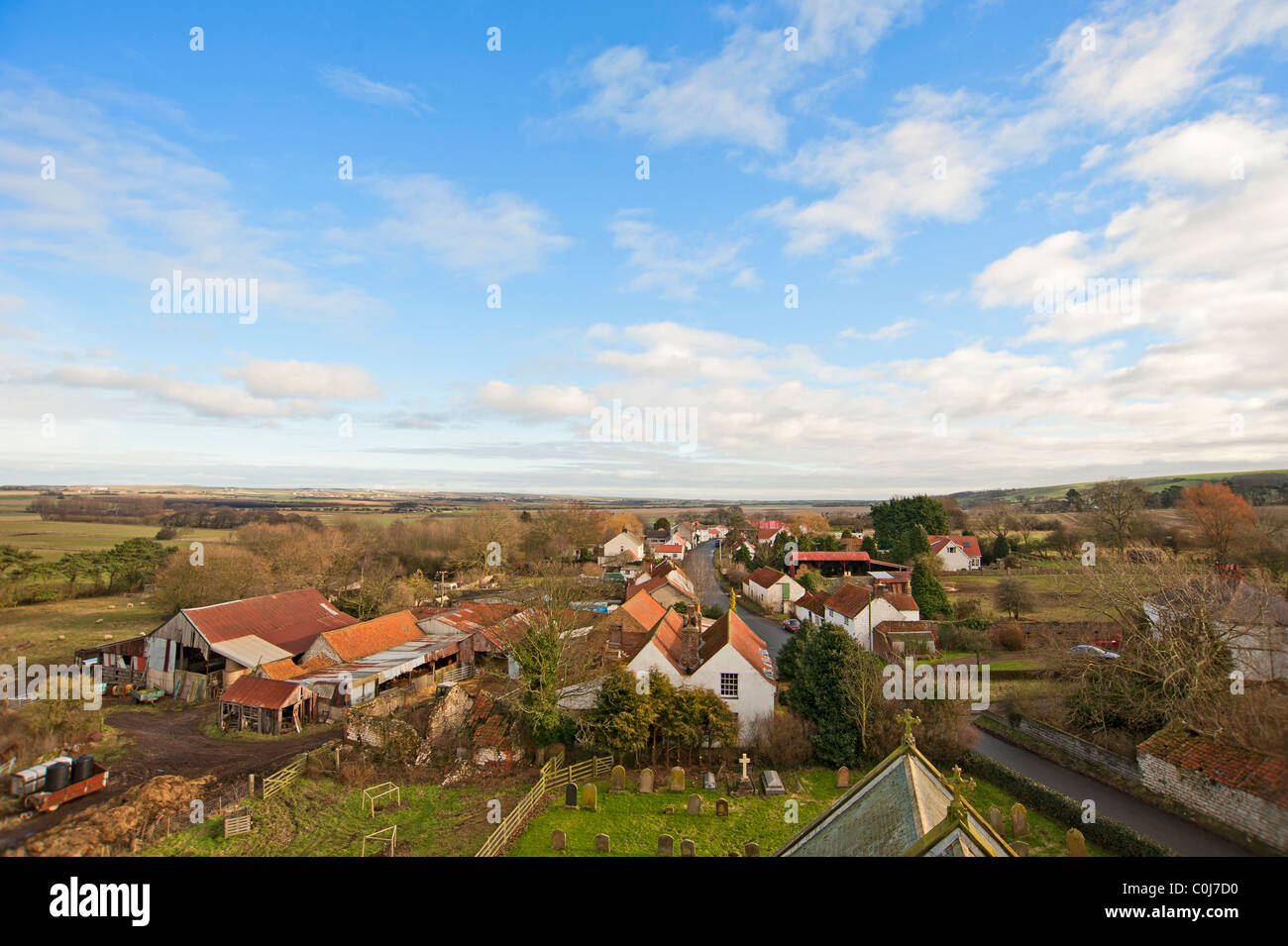 Aerial view over a countryside farming community with church graveyard ...