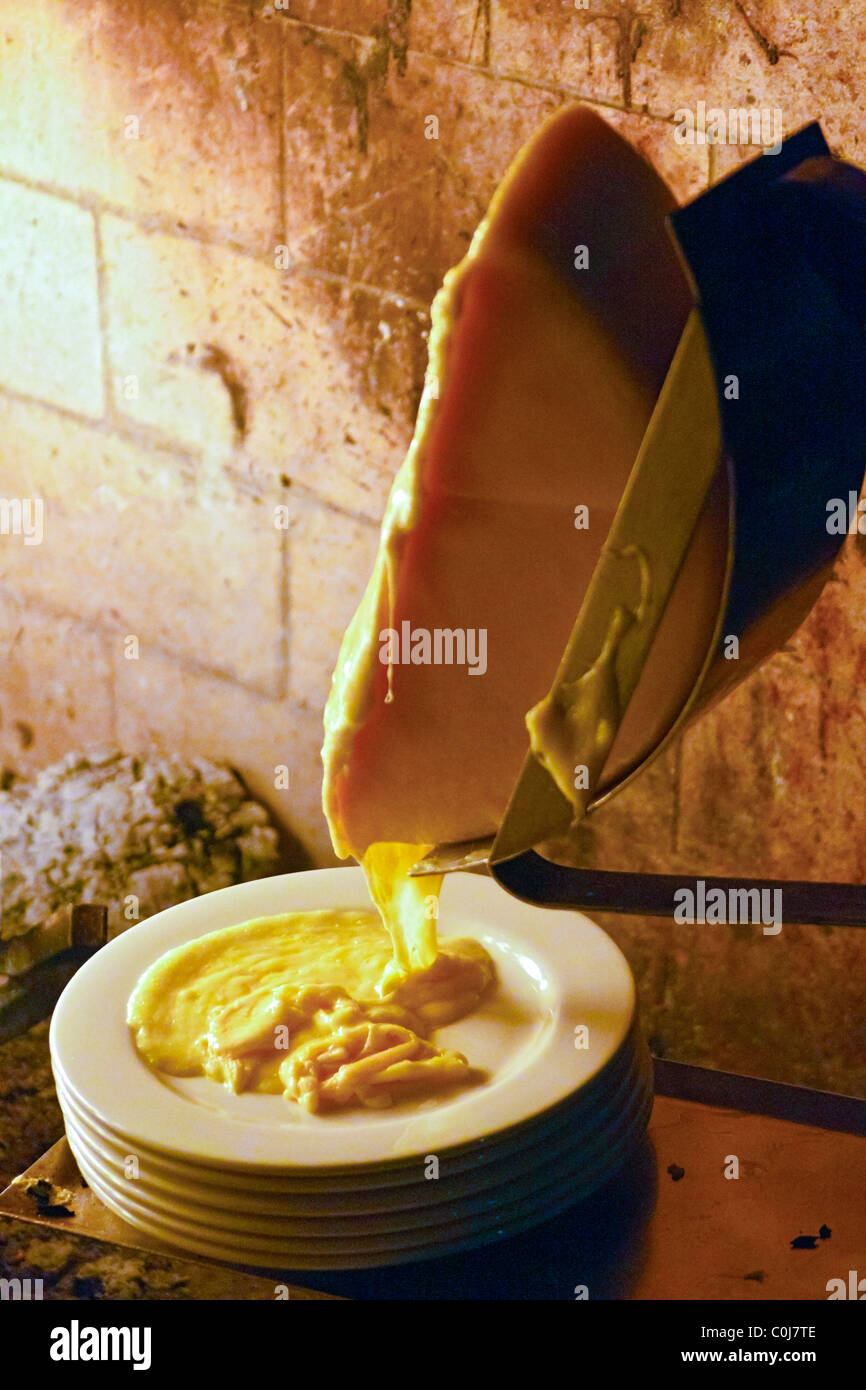Wheel of raclette cheese melting before fireplace Stock Photo - Alamy