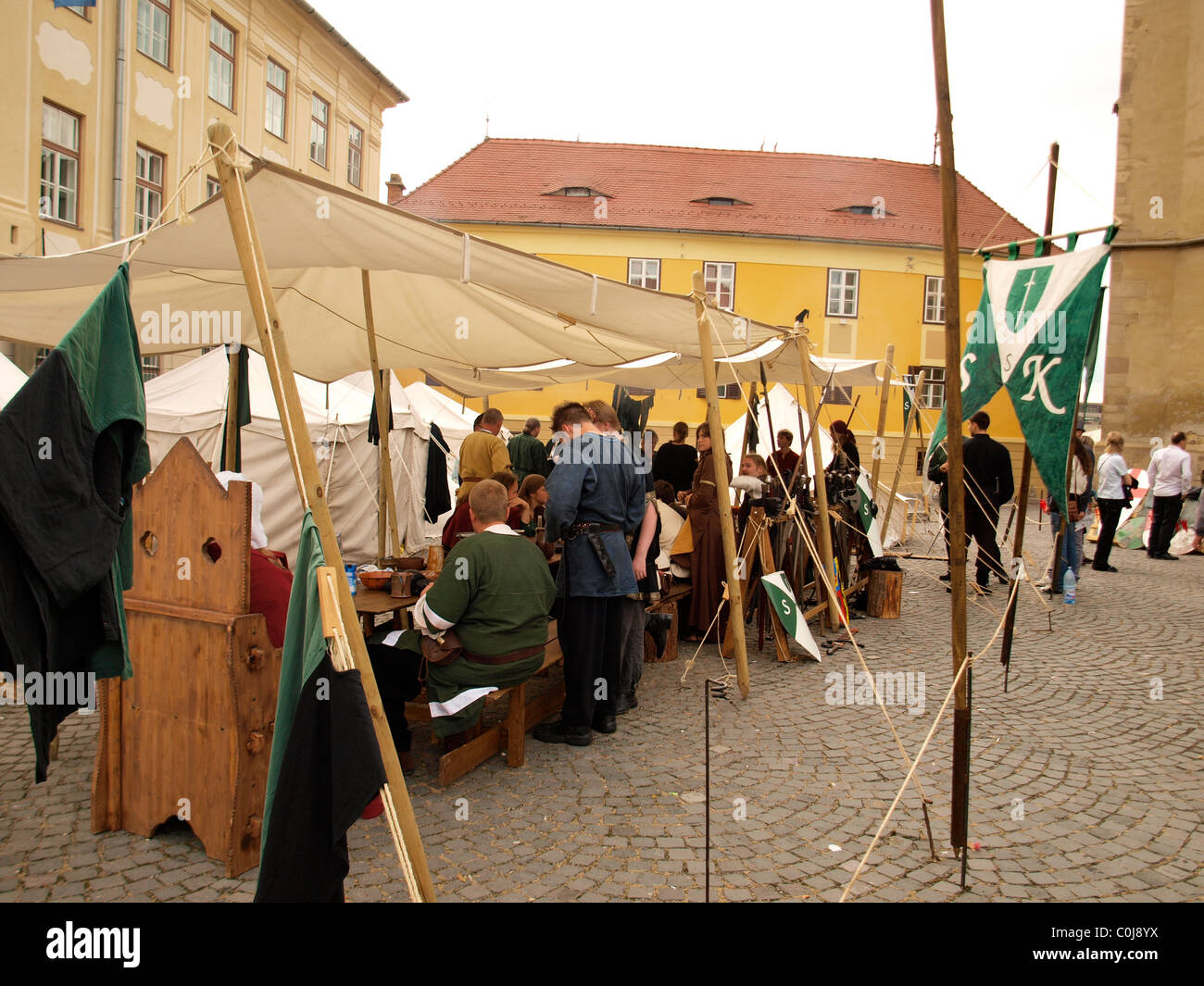 People dressed as knights and eating around a wooden table Medieval ...