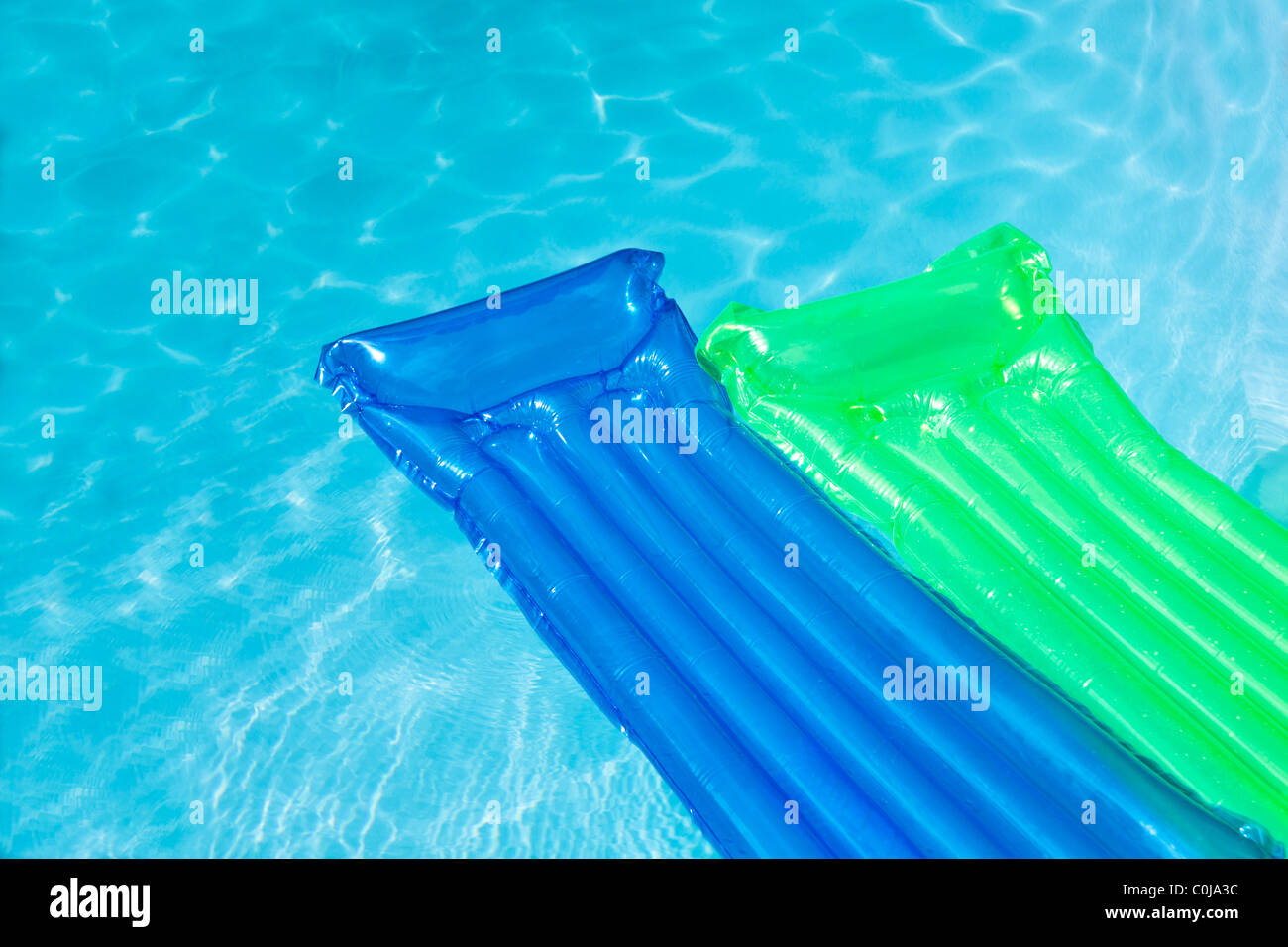 Swimming pool with two green and blue lilos Stock Photo - Alamy