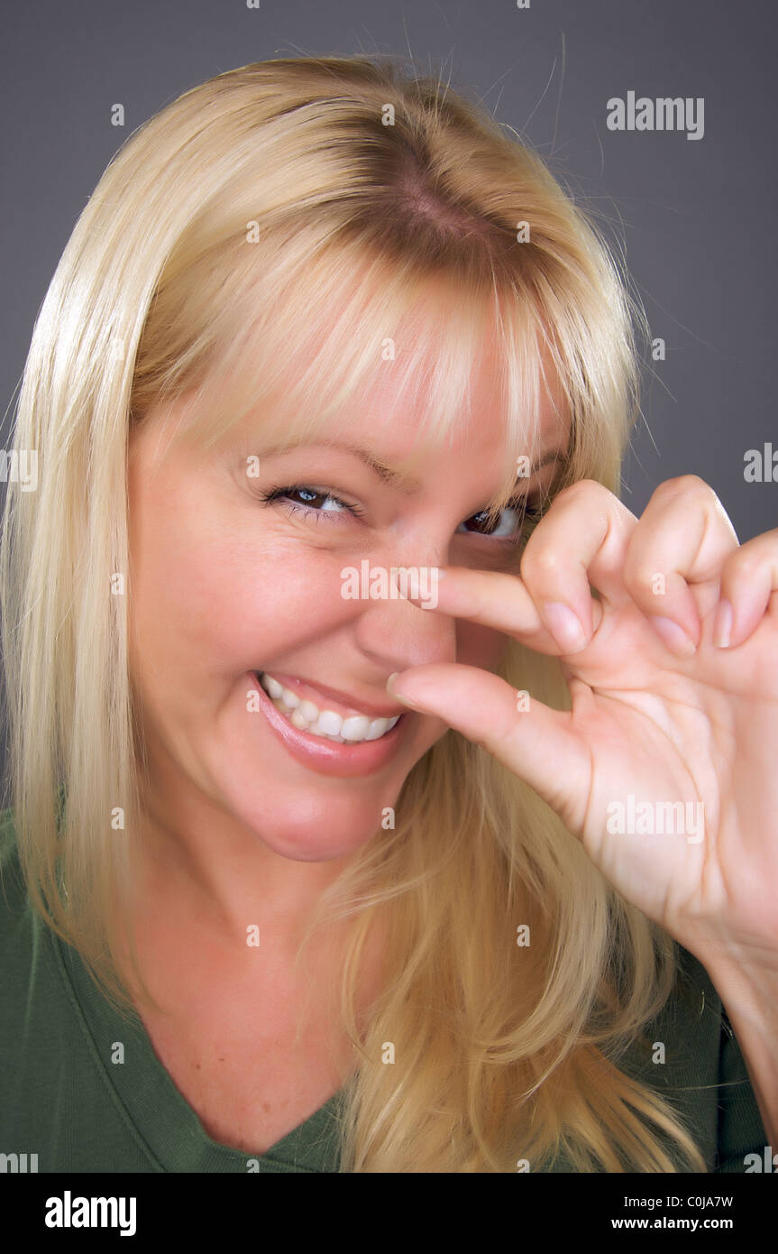 Woman Indicating A Little Bit with Her Hand Against a Grey Background ...