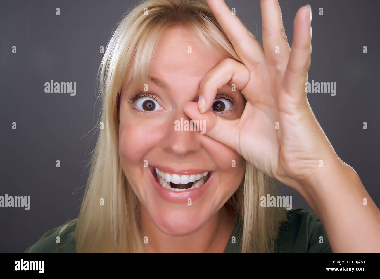 Goofy Woman with Okay Sign in Front of Face Against a Grey Background ...